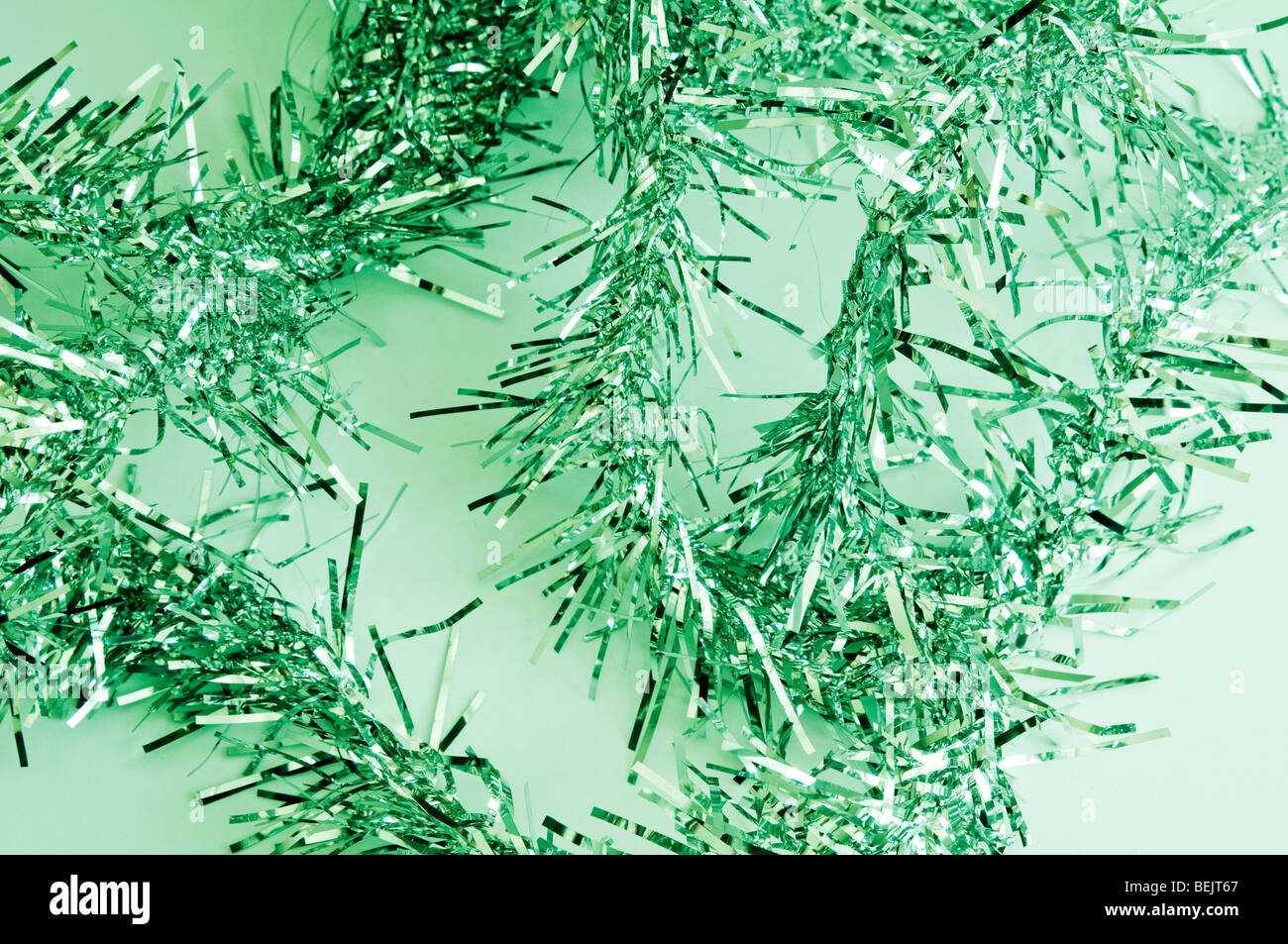 Green Christmas Tinsel on a pale green background Stock Photo - Alamy