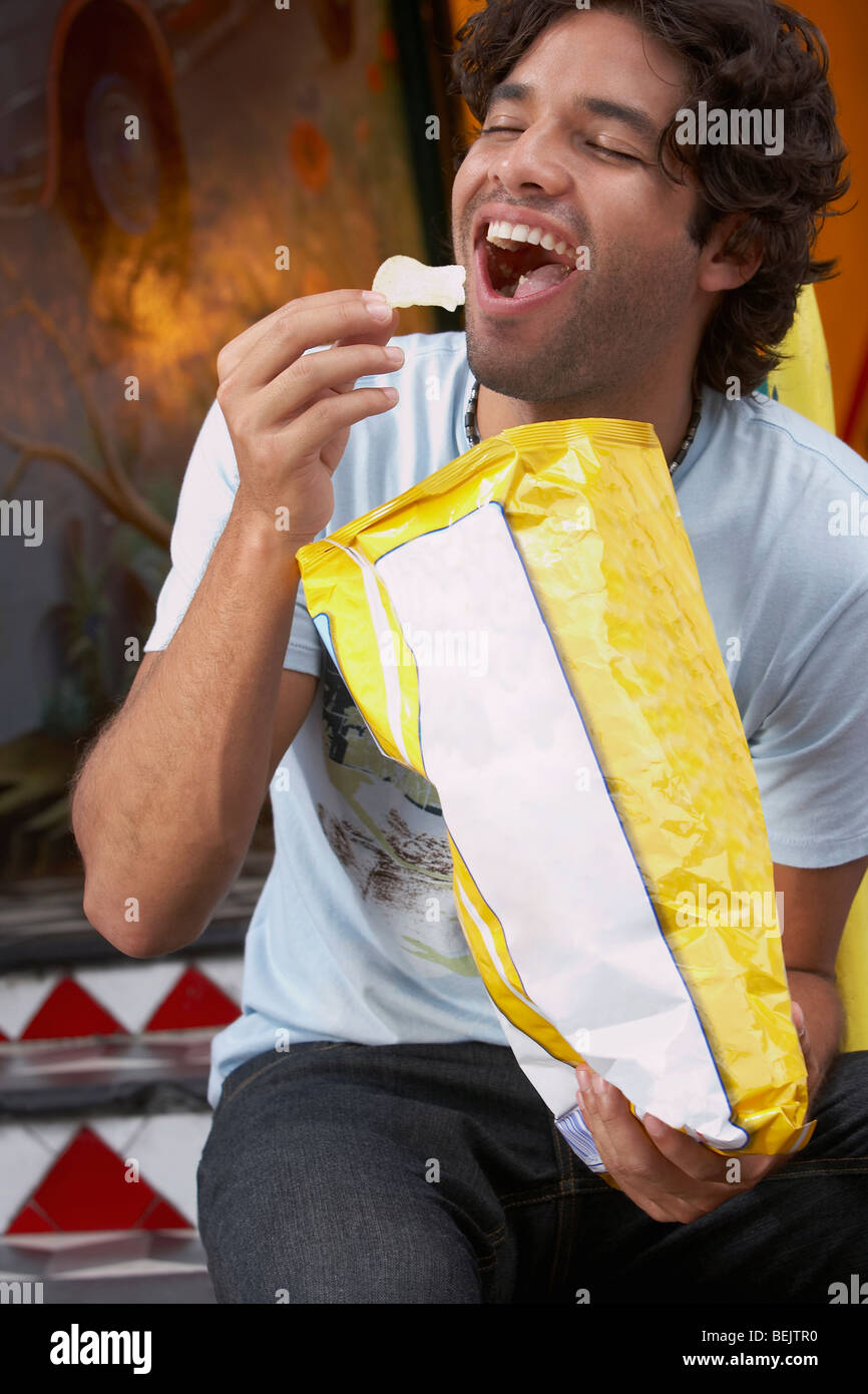 Close-up of a young man eating potato chips Stock Photo - Alamy