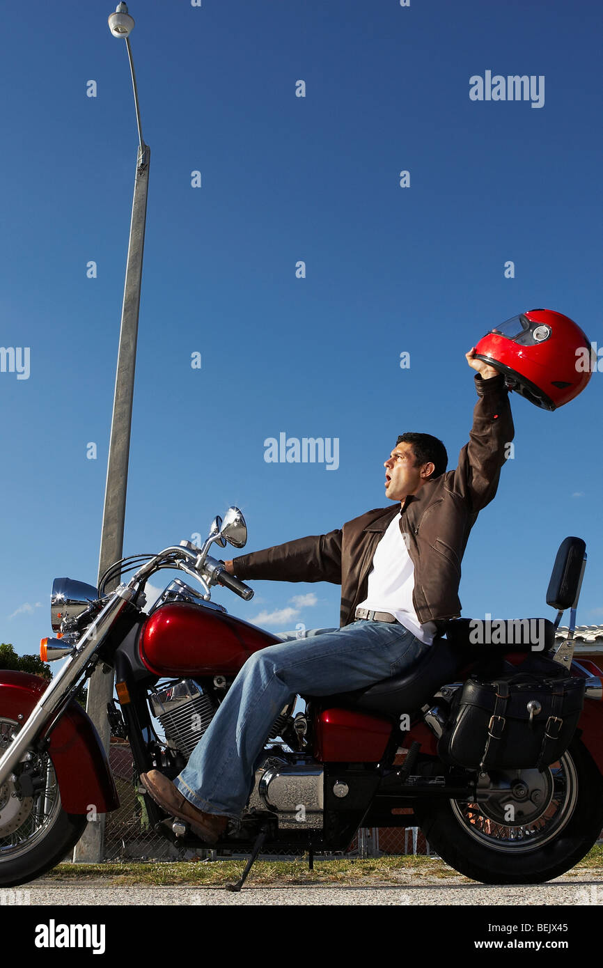 Side profile of a mid adult man sitting on a motorcycle and raising his ...