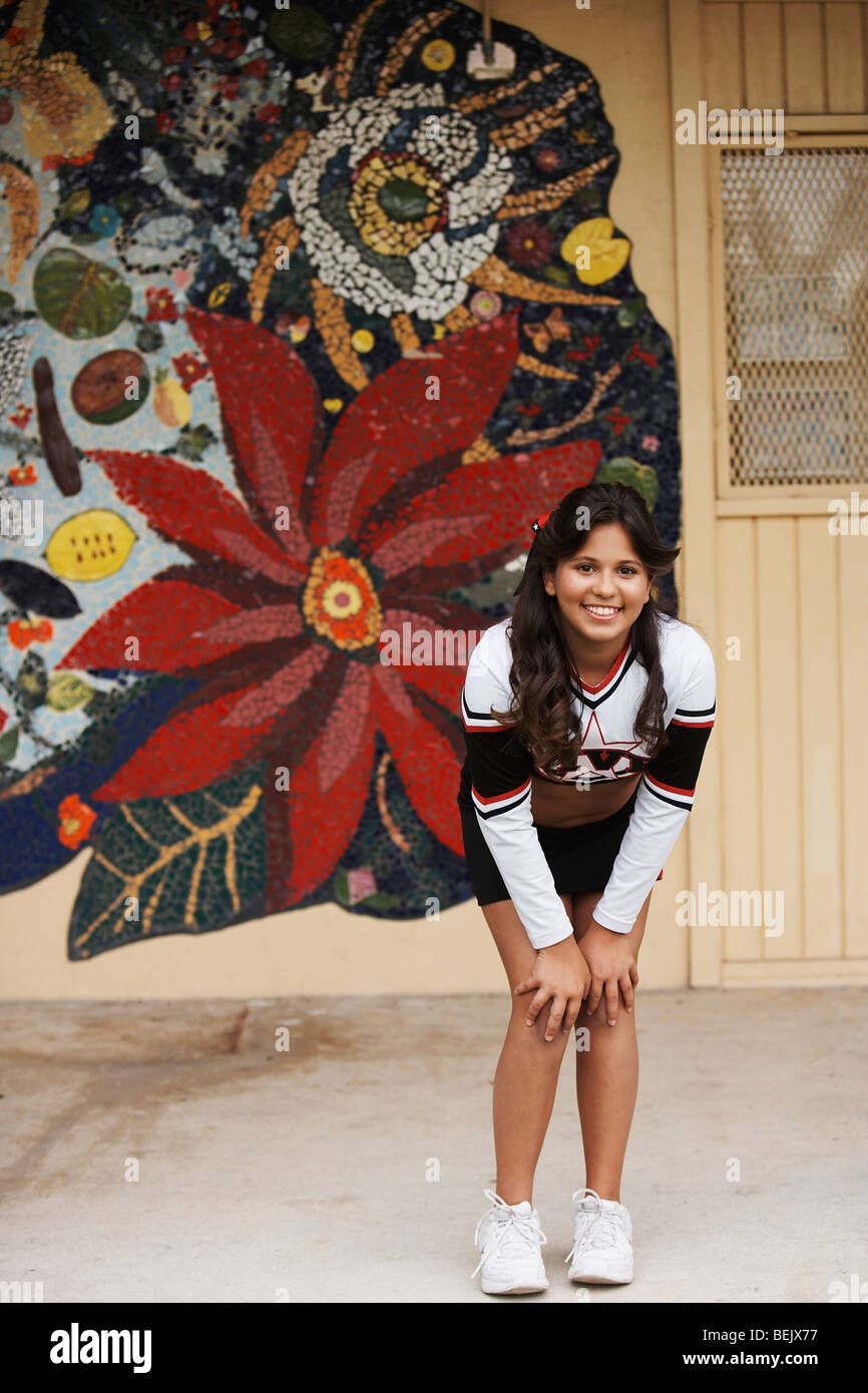 Portrait of a girl bending forward with her hands on her knees and ...