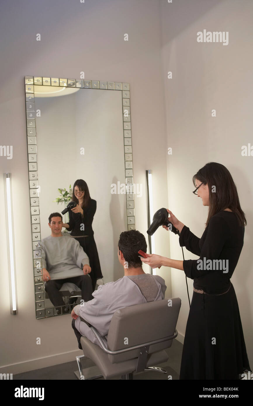 Side profile of a female hairdresser cutting hair of a mid adult man ...