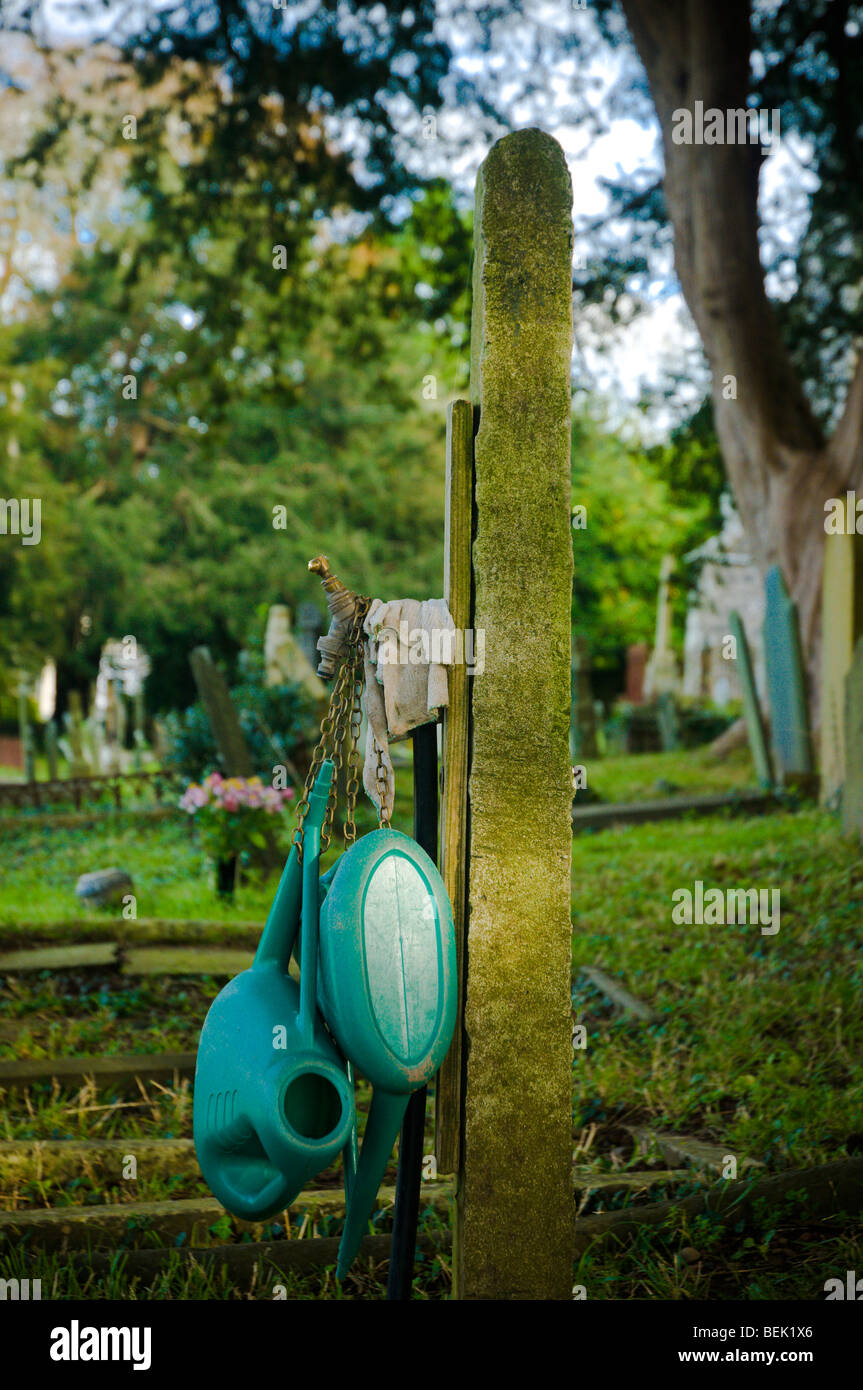 Watering cans hing on a post at a graveyard. These are placed here to ...