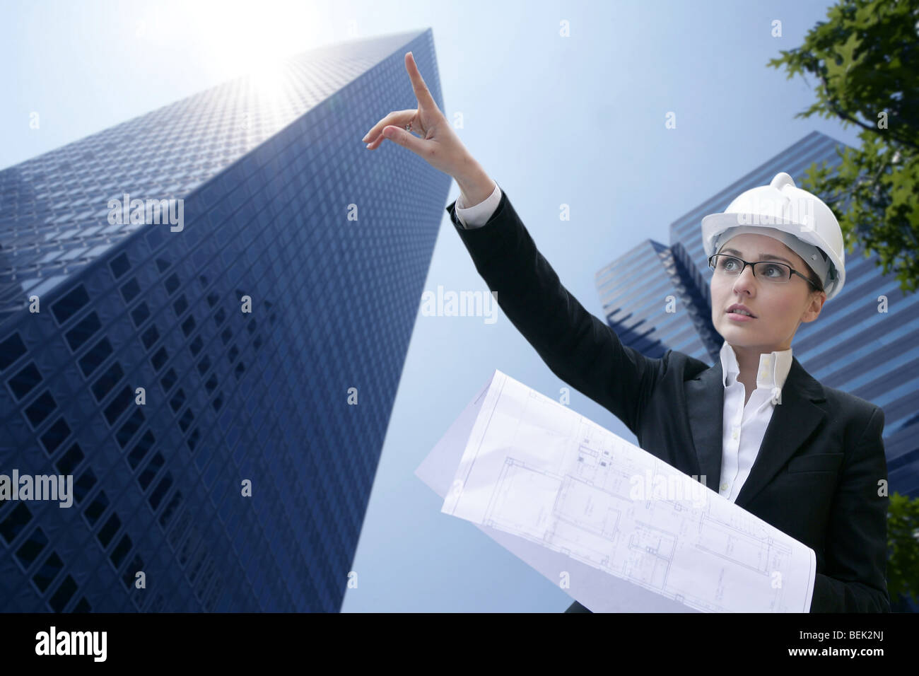 Young beautiful architect engineer with hardhat and plans in front city ...