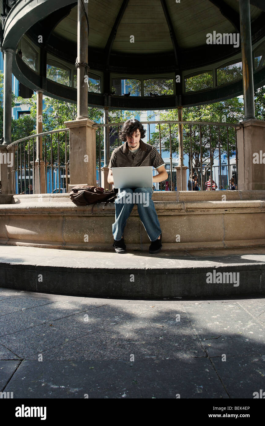 Young man sitting and using a laptop Stock Photo - Alamy