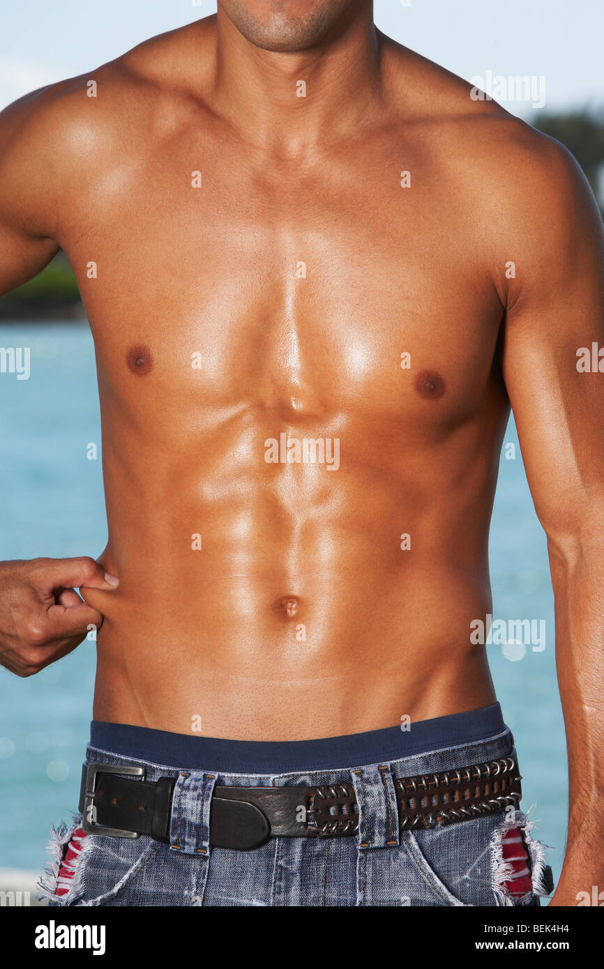 Mid section view of a bare chested young man pinching his skin Stock ...