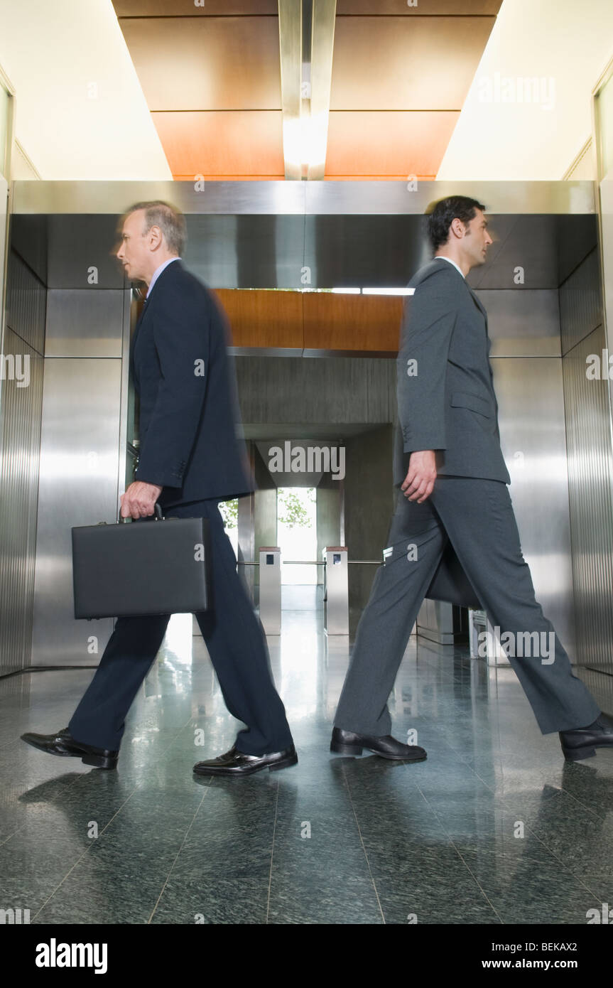 Businessmen moving towards elevators Stock Photo - Alamy