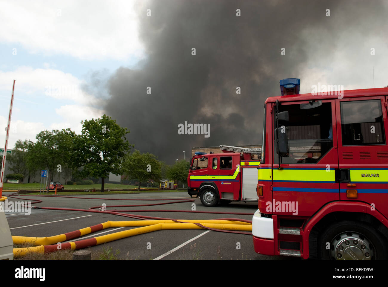 Firefighers and appliance at scene of large fire with Black smoke Stock ...