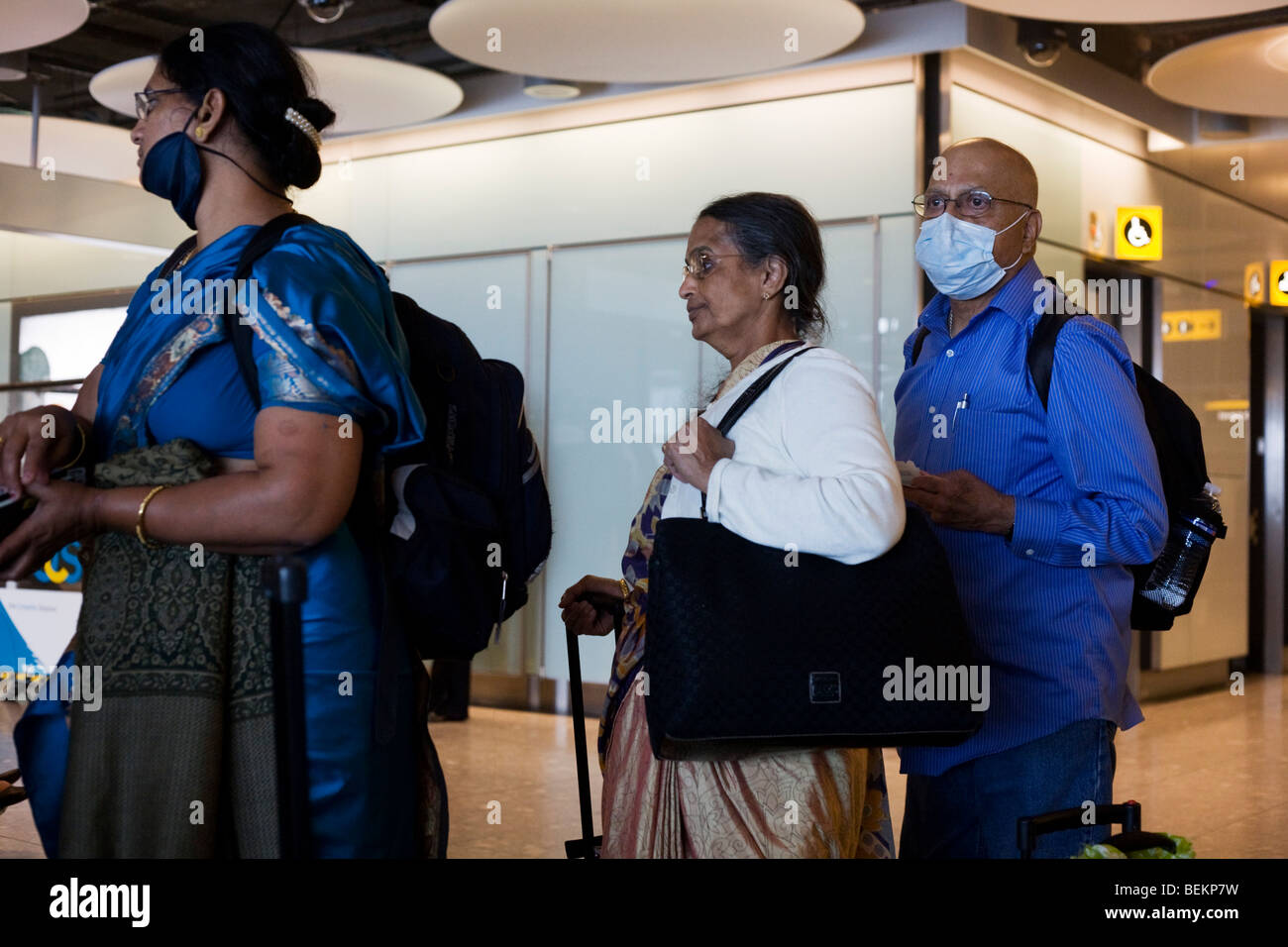 Airline passengers recently arrived from India wait in line at Heathrow ...
