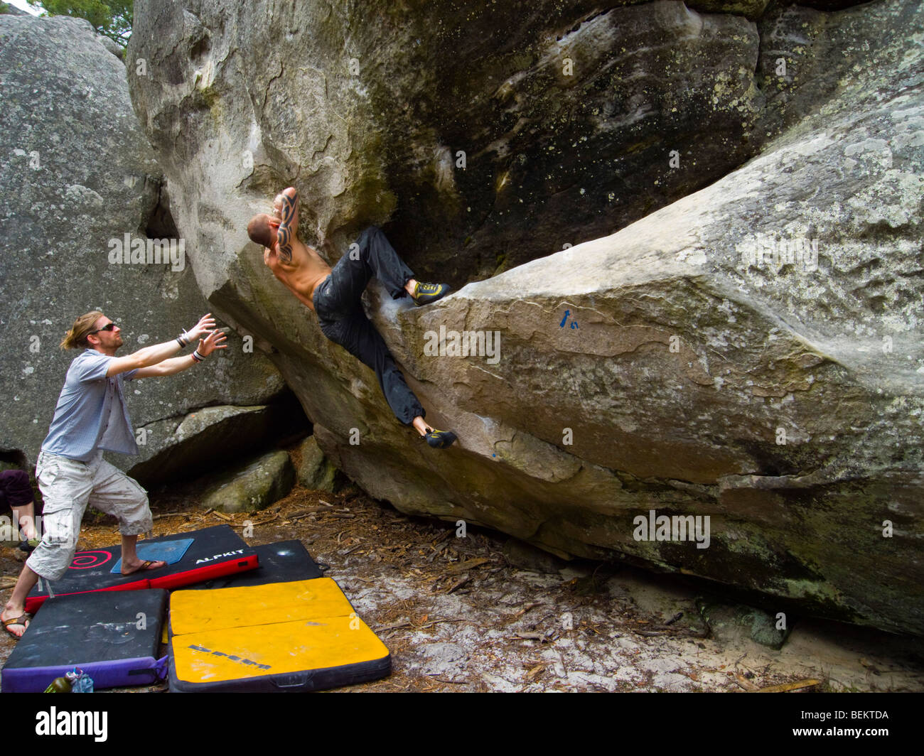 Two male climbers one spotting the other on a boulder problem Stock ...