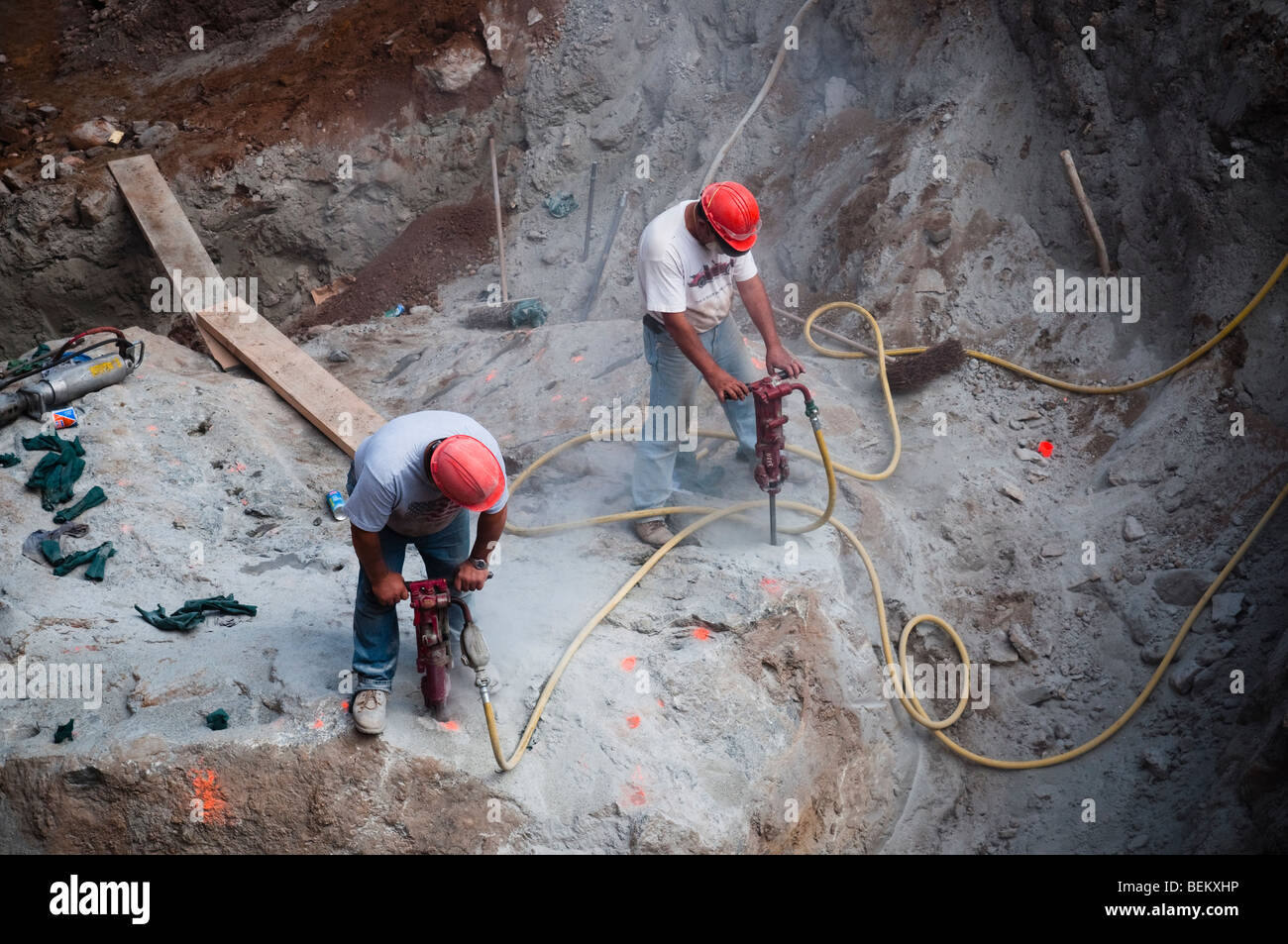 Two Construction Workers Use Jackhammers To Excavate Rock At ...