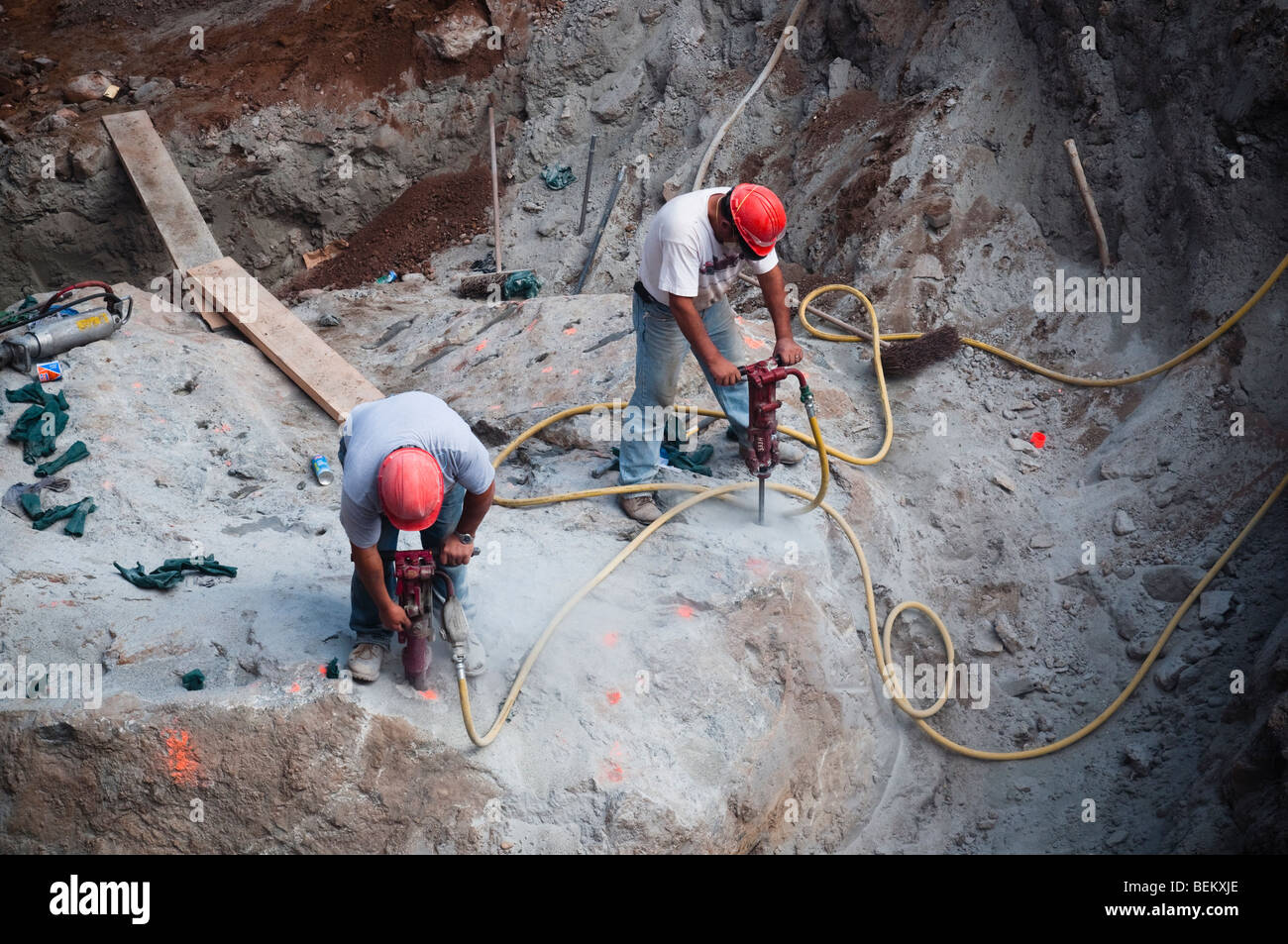Two Construction Workers Use Jackhammers To Excavate Rock At ...