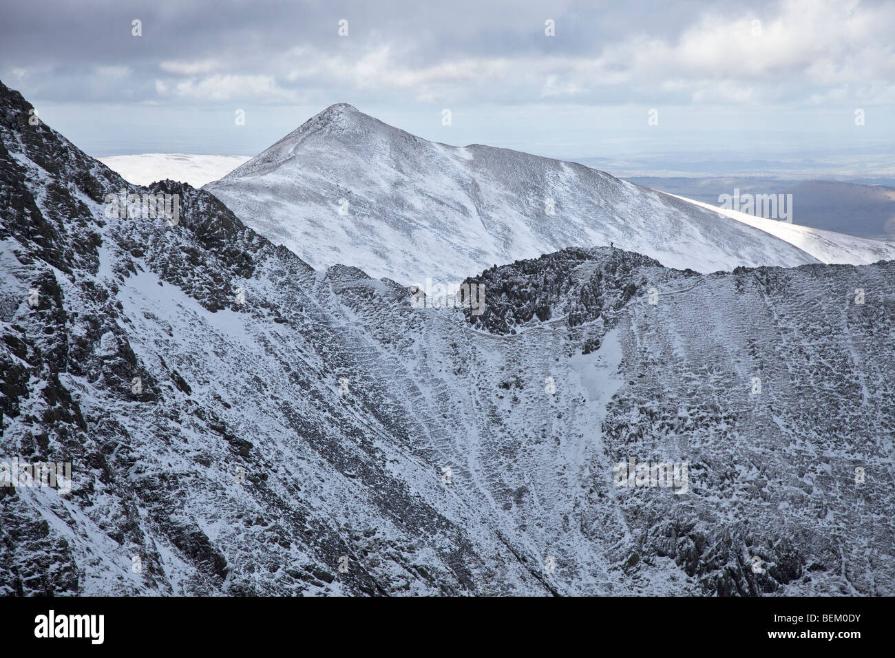 A lone walker crossing Striding Edge in winter, Catstye Cam beyond ...
