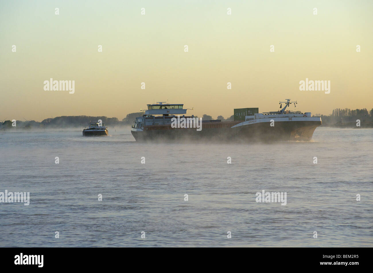 Inland barges sailing through mist on River Waal (Rhine) during autumn ...