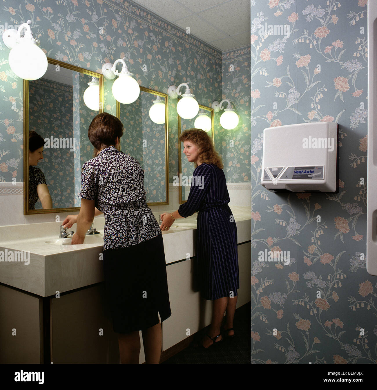 two women using wash basins in ladies rest room Stock Photo - Alamy