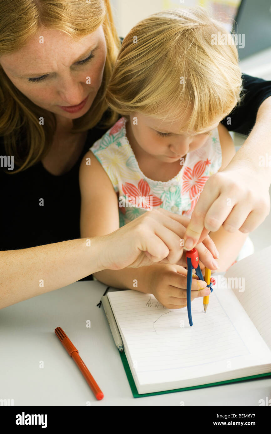 Woman helping little girl draw with compass Stock Photo - Alamy