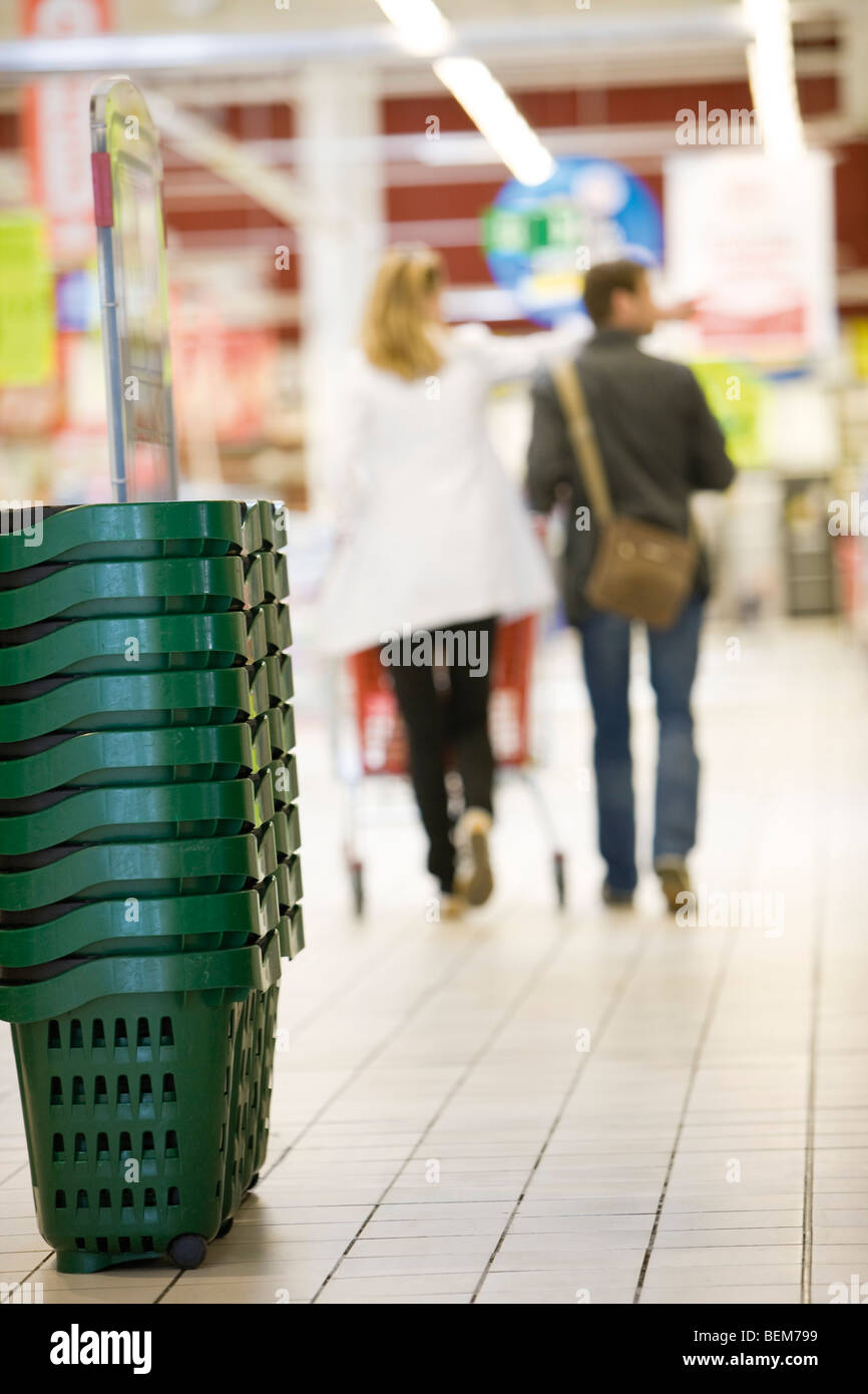 Stack of shopping baskets, shoppers in background Stock Photo - Alamy