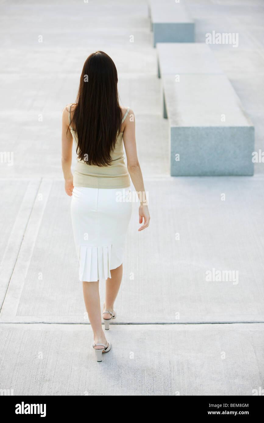 Woman walking in city square, rear view Stock Photo - Alamy