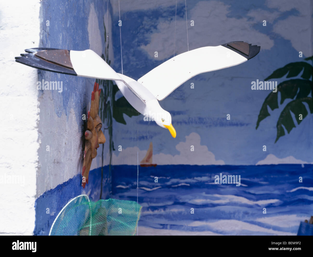 Close-up of wooden seagull mobile against sea mural on garden wall ...