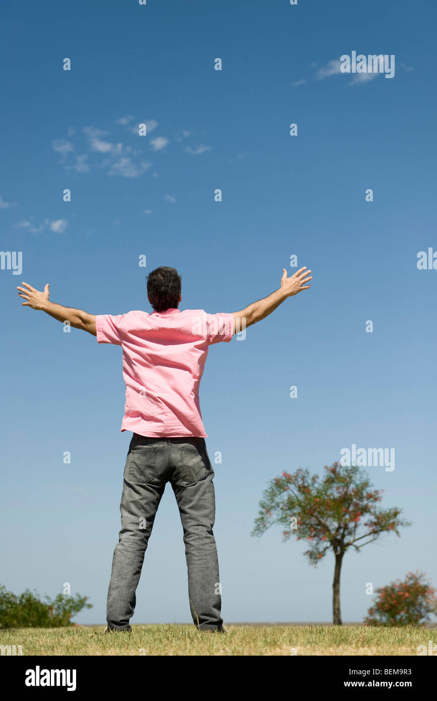 Man standing outdoors with arms raised, full length, rear view Stock ...