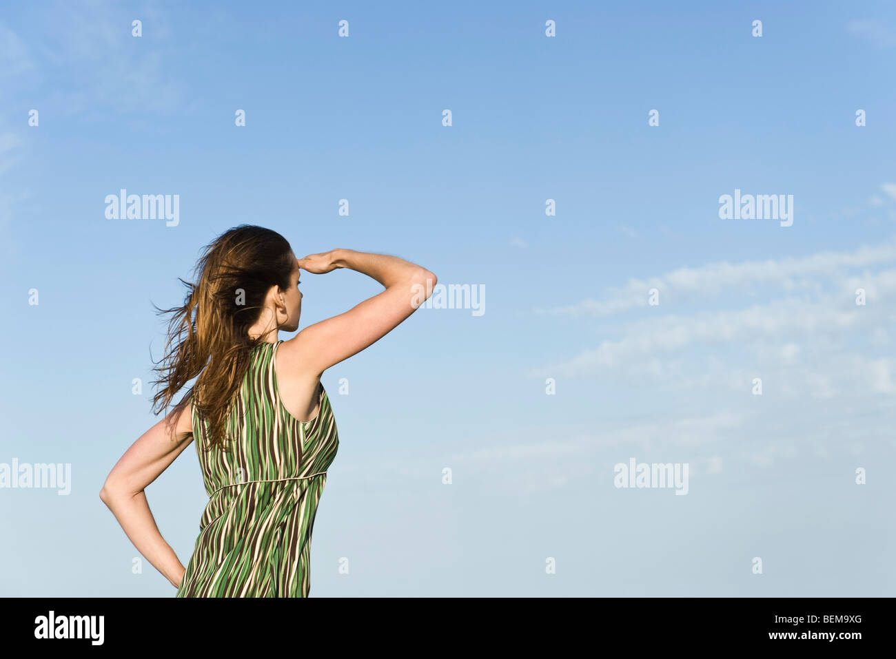 Woman standing in wind with hand shading eyes, sky in background Stock ...