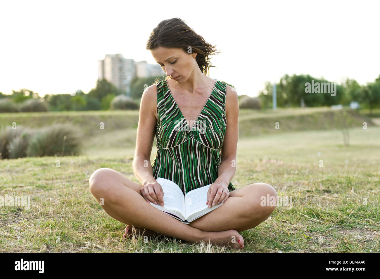 Woman sitting on grass, reading book Stock Photo - Alamy