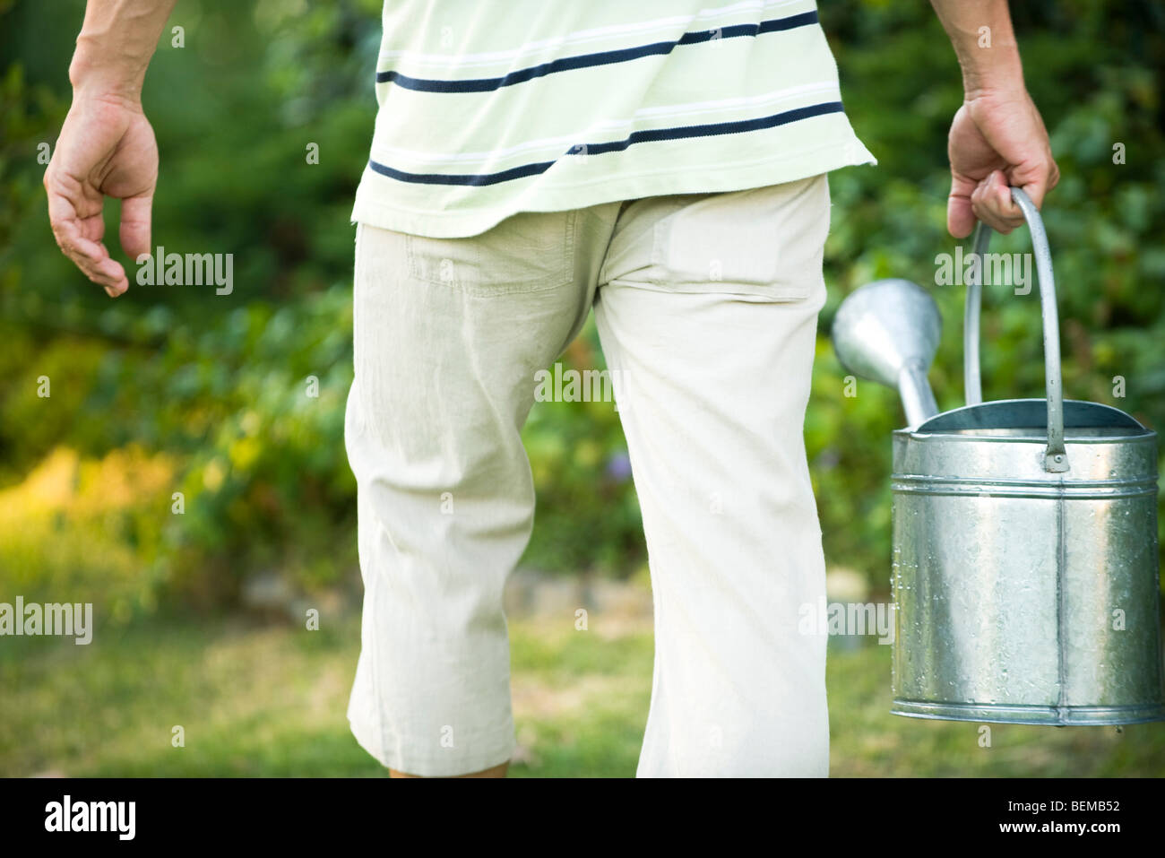 Carrying watering can, rear view Stock Photo - Alamy