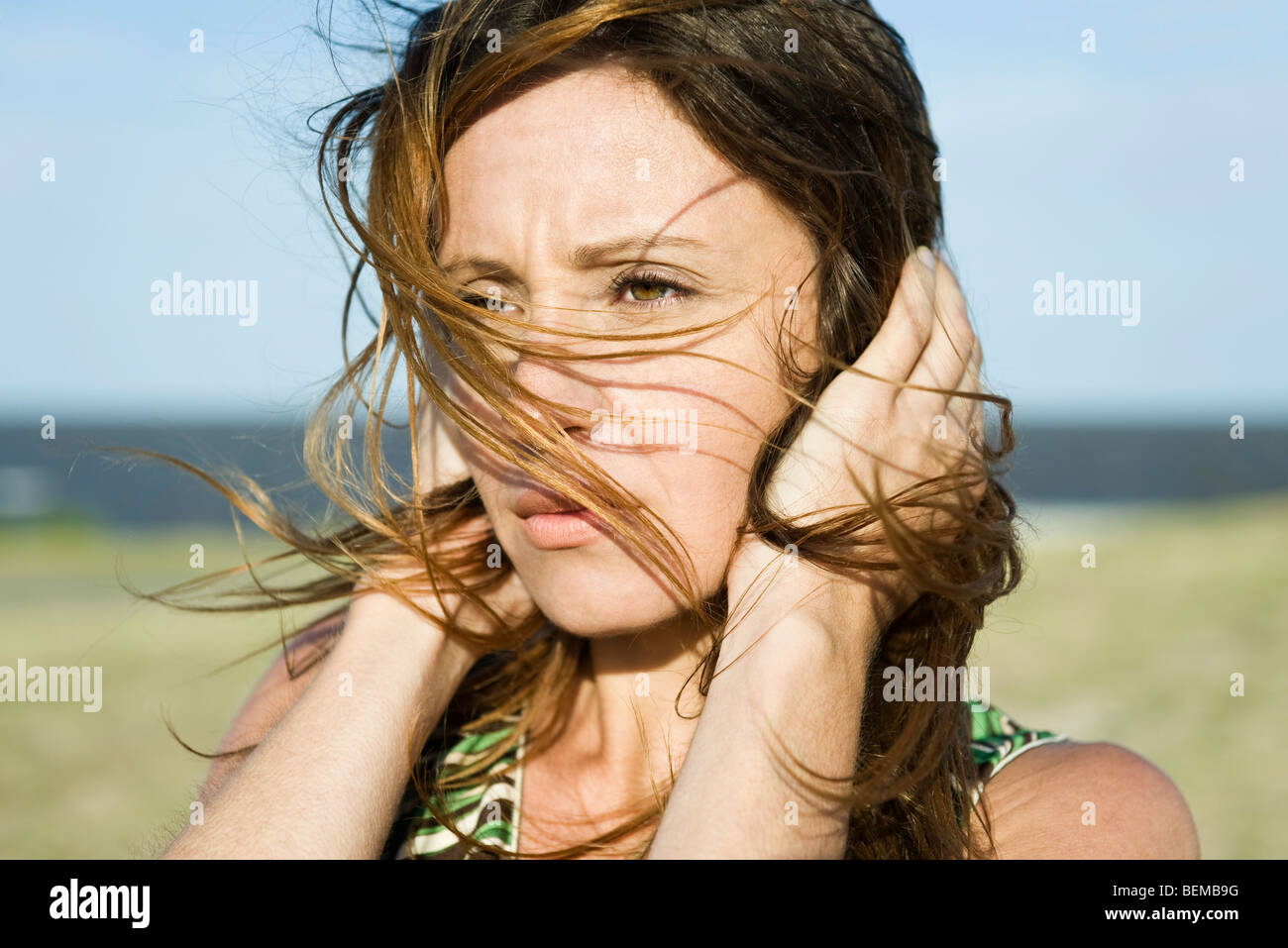 Woman standing in wind, hands holding hair down, close-up Stock Photo ...