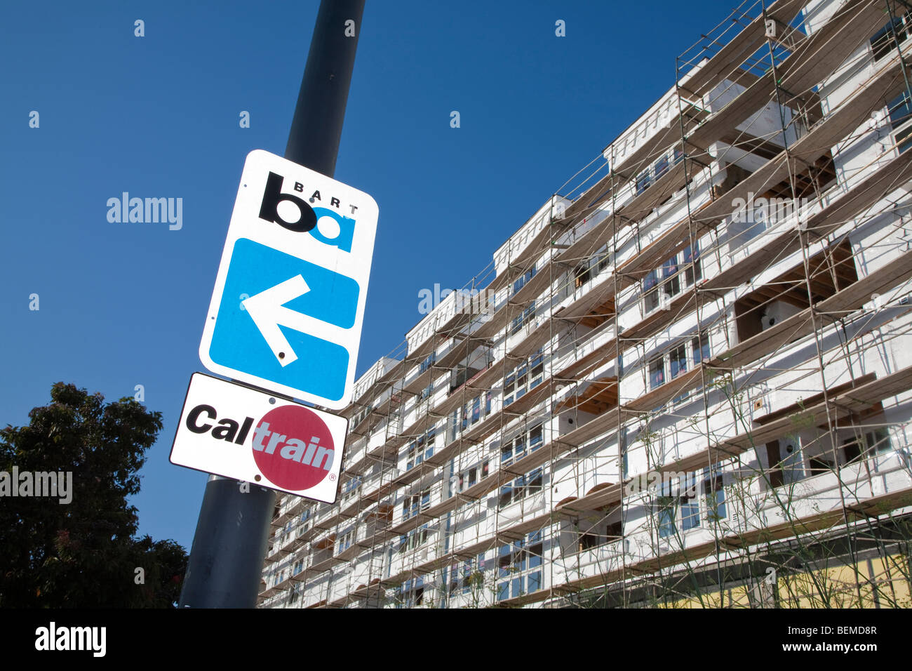 A low angle view of BART and Caltrain road signs by a scaffolded condo ...