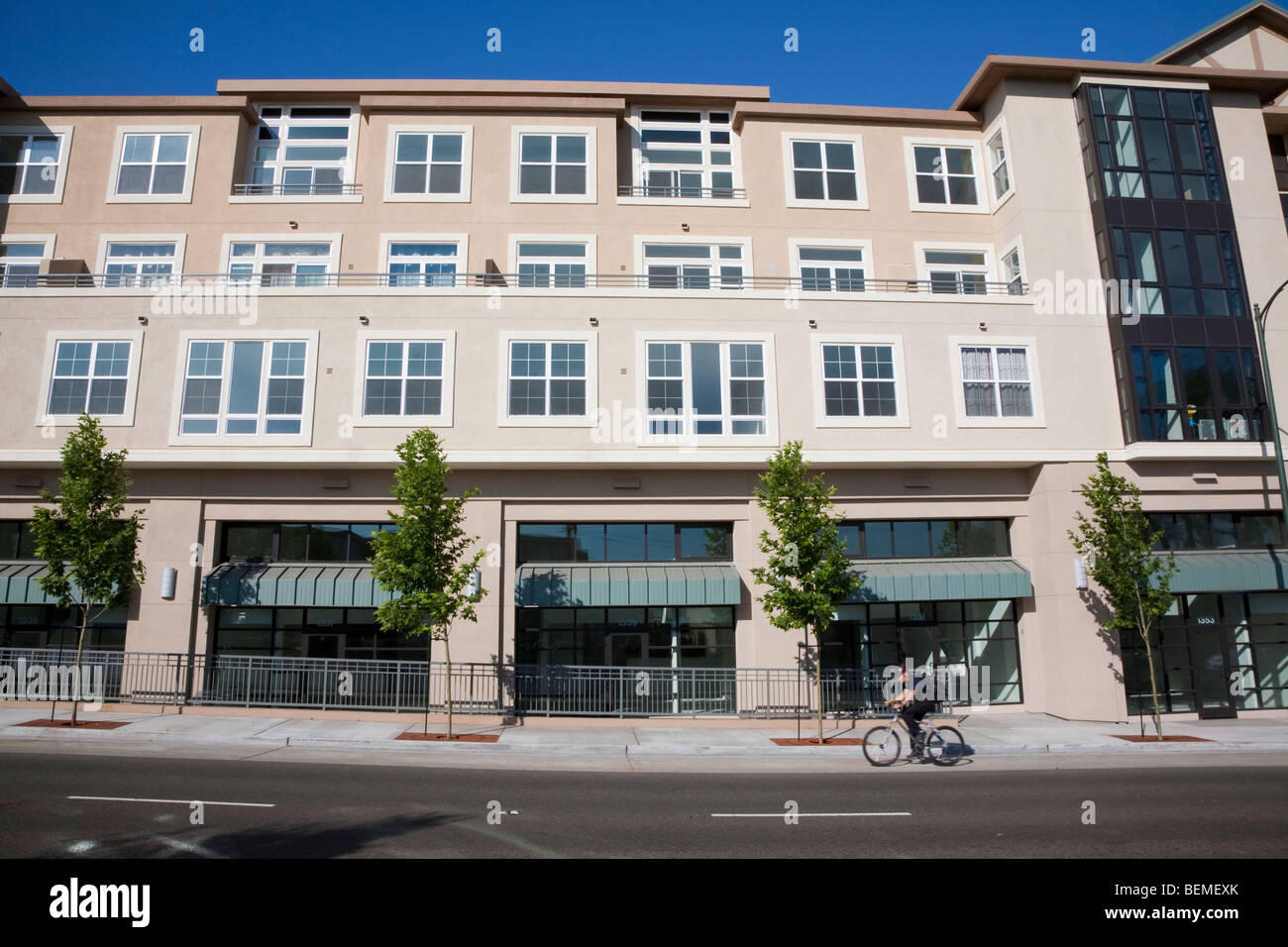 Bicyclist rides in front of mixed use housing development. Residential ...