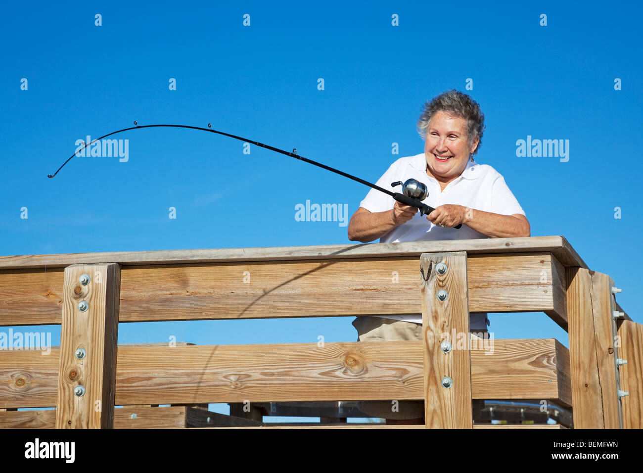 Retired senior woman on a pier in Florida, reeling in a big fish Stock ...