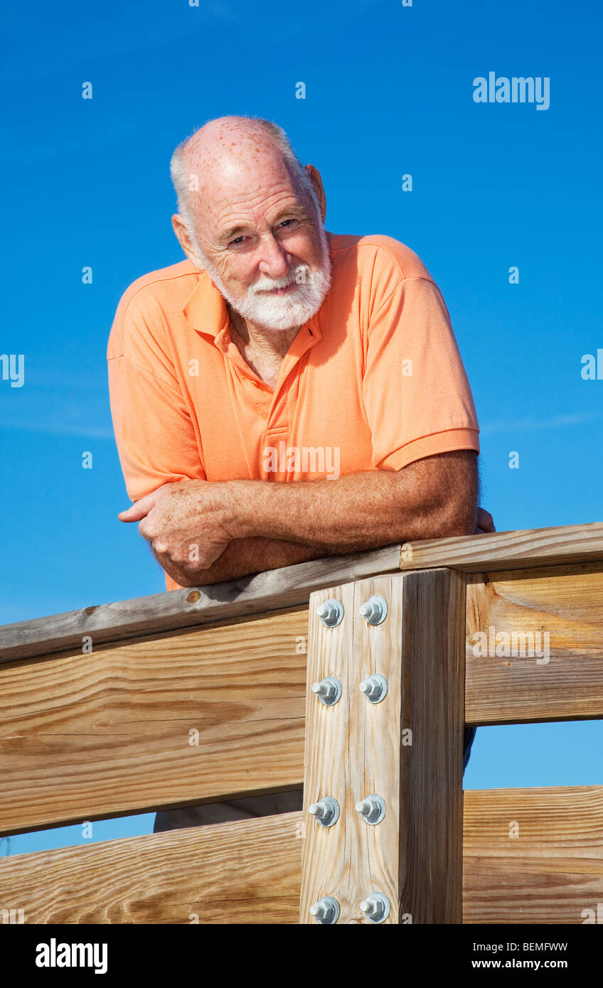 Portrait of a handsome, fit senior man leaning on a wood railing Stock ...