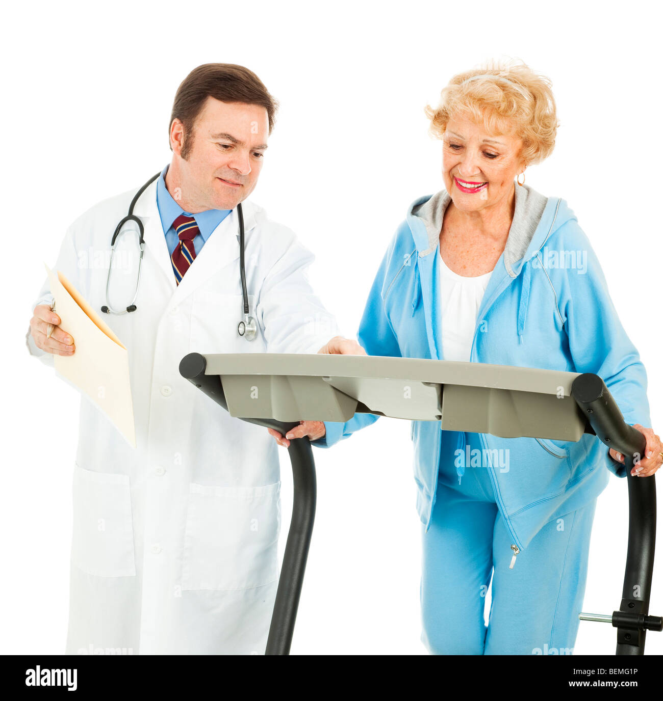Doctor supervising a fit senior woman as she works out on a treadmill ...