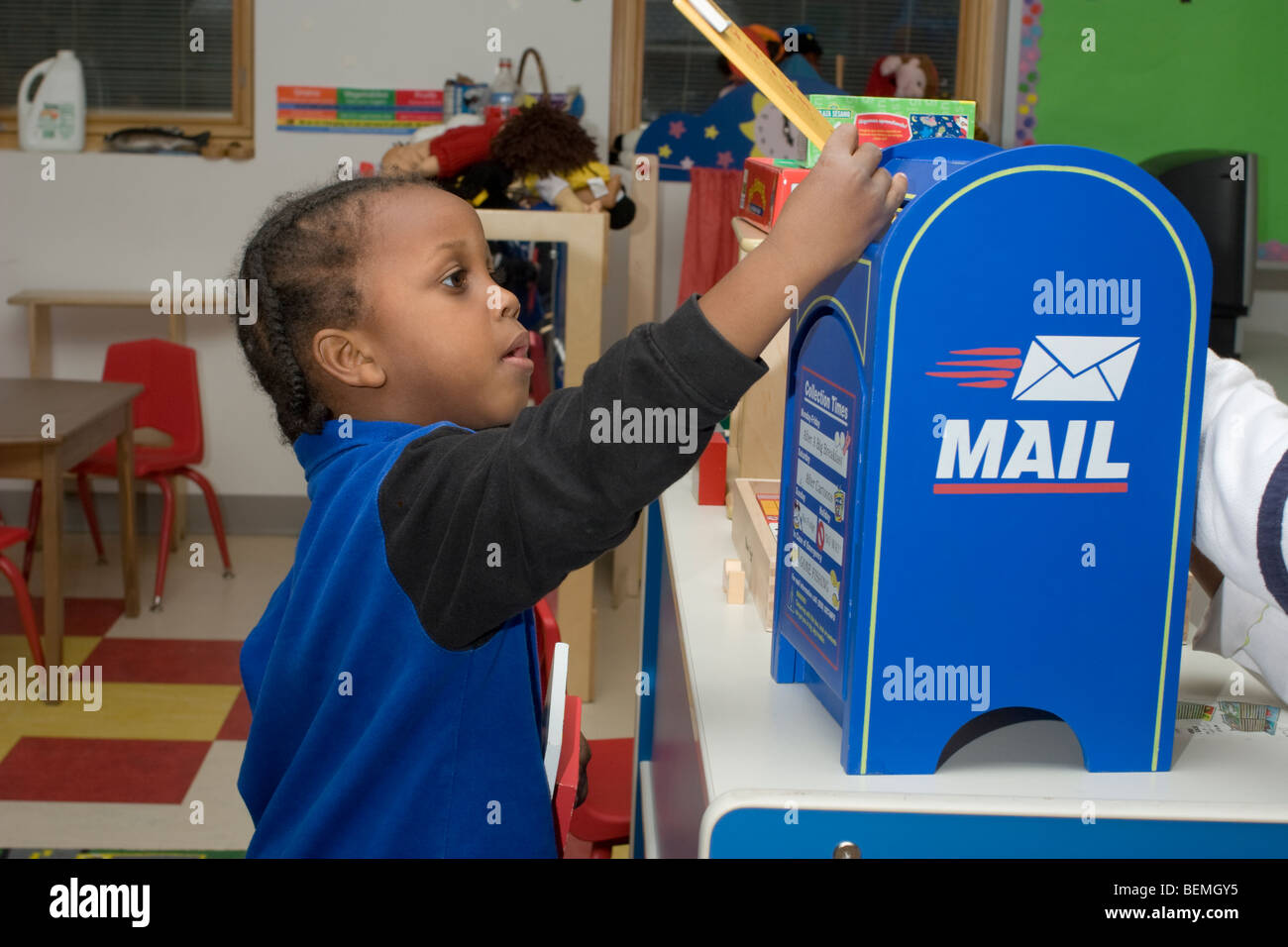 African-American preschool boy putting a letter in a mailbox in the ...