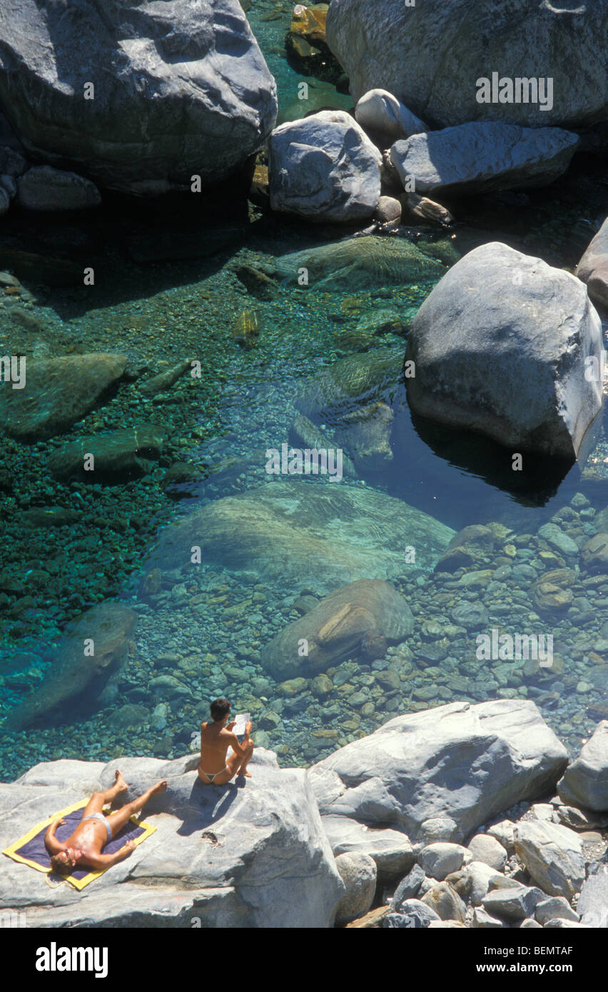 Couple sunbathing at River Verzasca, Verzsasca Valley, Ticino ...