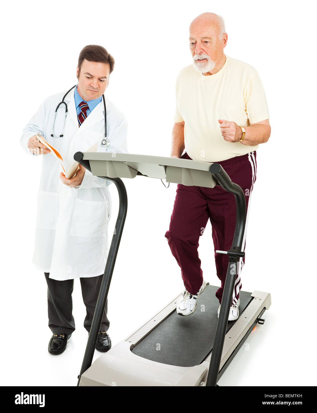 Senior man runs on a treadmill while his doctor charts his progress ...