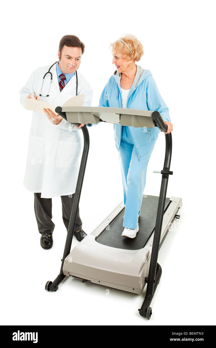 Senior woman exercising on a treadmill while her doctor monitors her ...