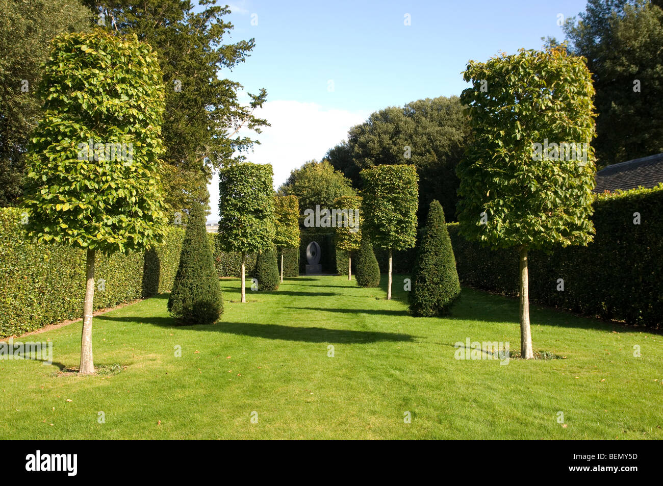 a view seen through two lines of sculptured trees and shrubs neatly ...
