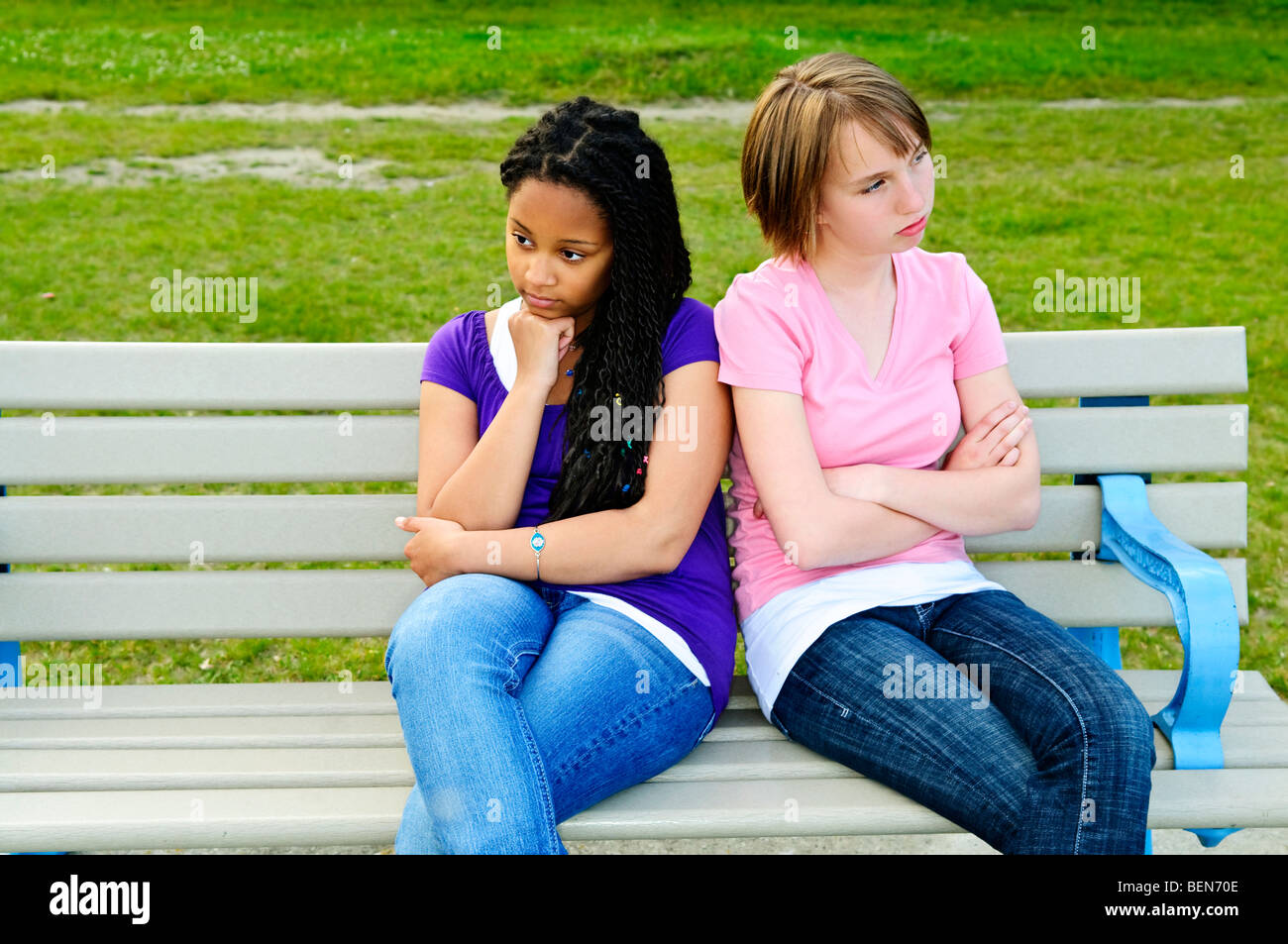 Two bored teenage girls sitting on bench Stock Photo - Alamy