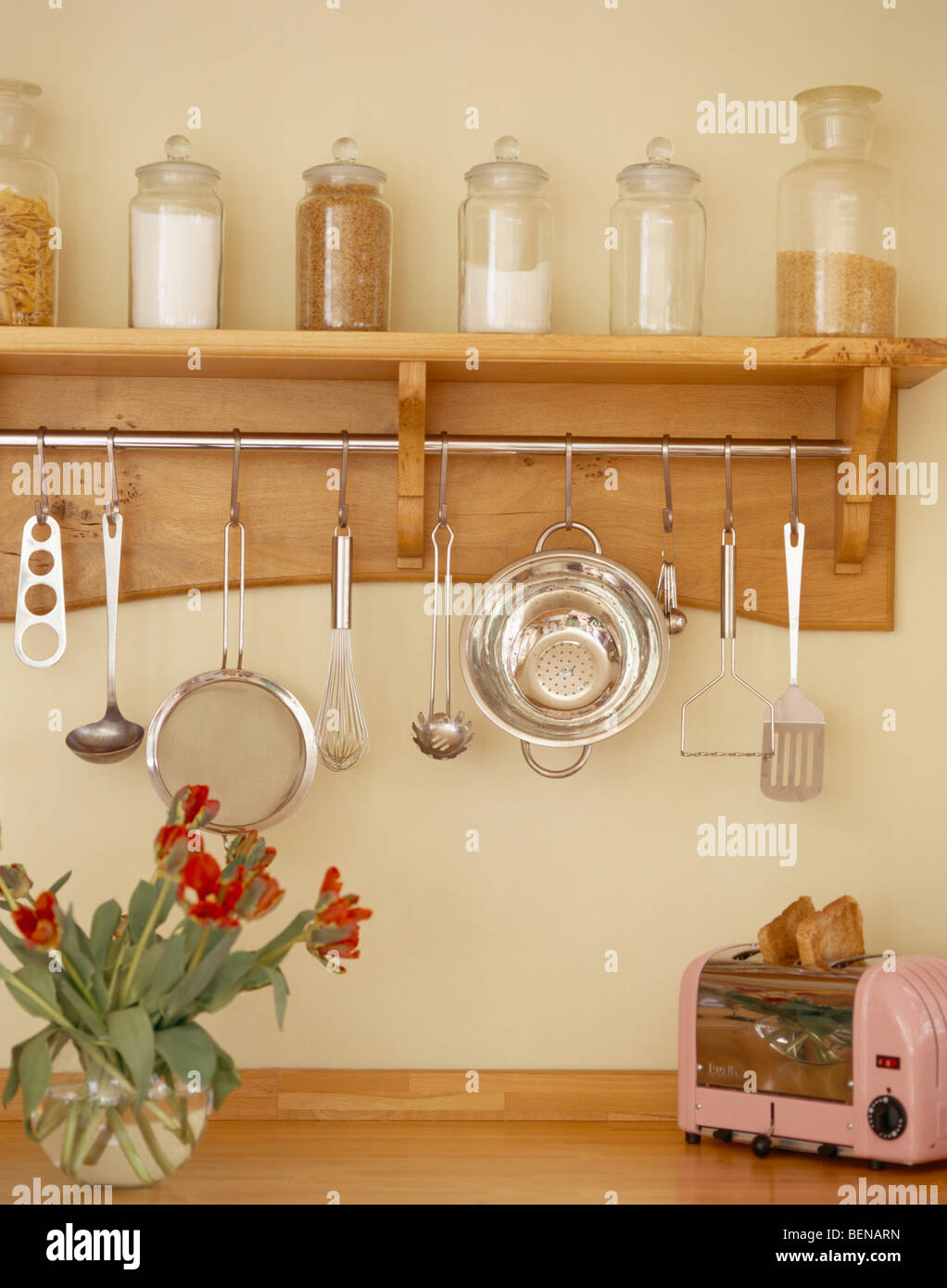 Close-up of glass storage jars on pine shelf above rack with metal ...
