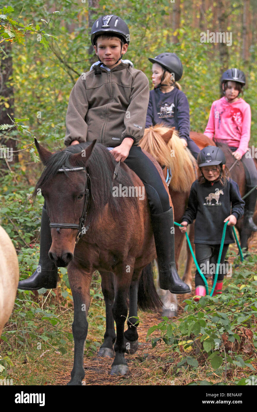 children riding on their ponies through a forest Stock Photo - Alamy