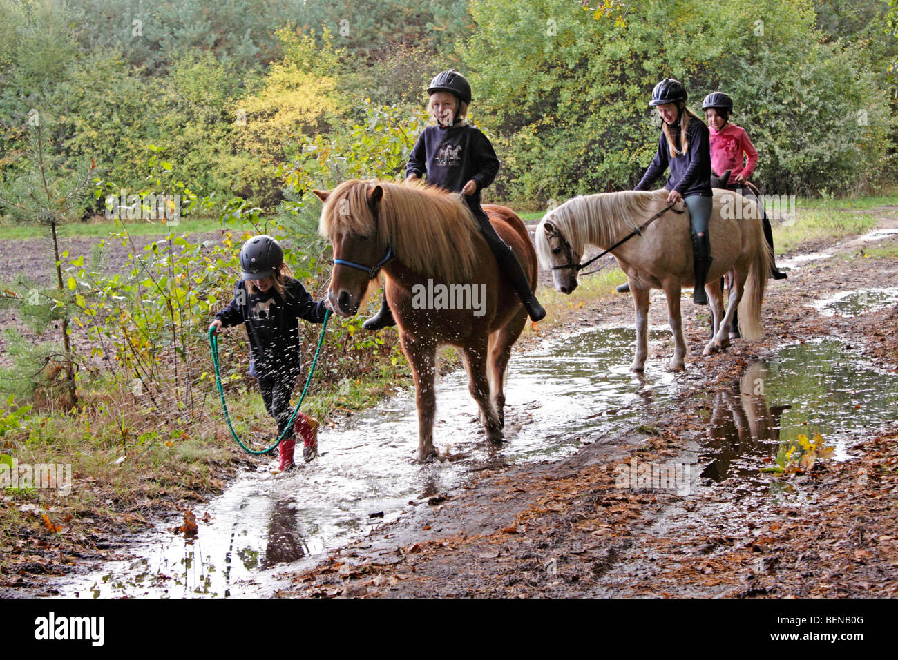 children riding on their ponies through a puddle Stock Photo - Alamy