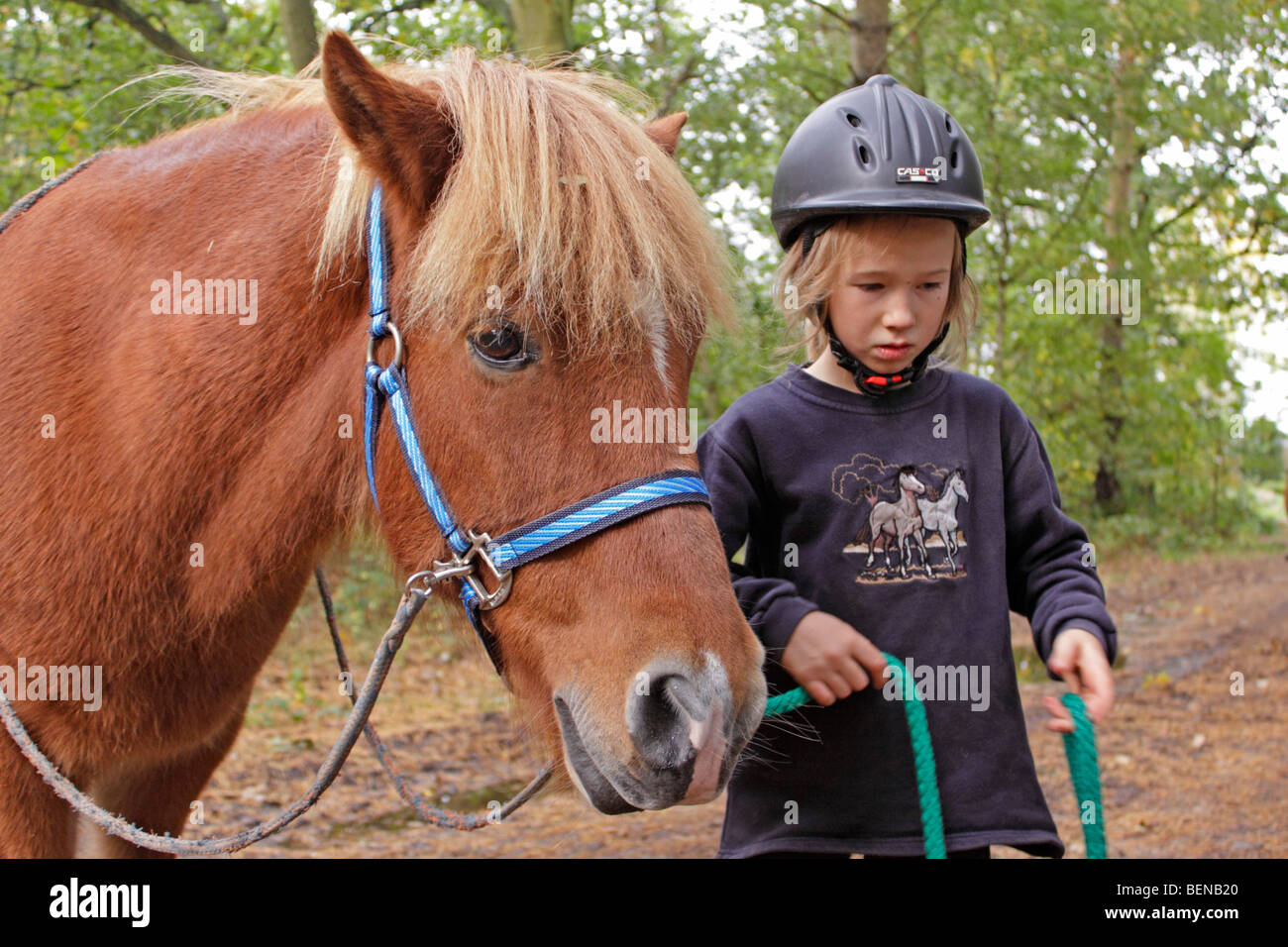portrait of a young girl standing beside her pony looking concerned ...