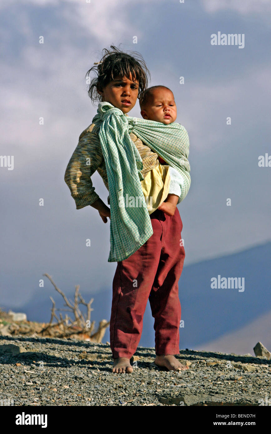 Semi-nomad Berber children, girl carrying little baby brother in sling ...