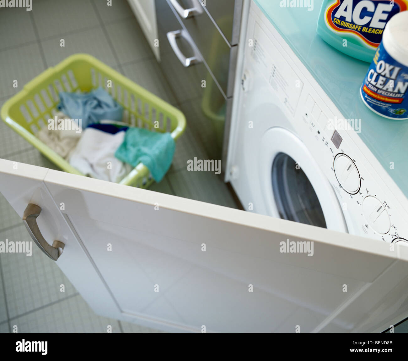 Close-up of plastic basket of laundry on floor below washing machine ...