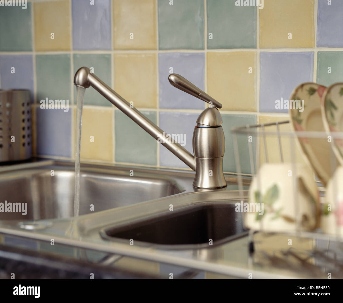 Close-up of stainless steel tap pouring water into double steel sink ...
