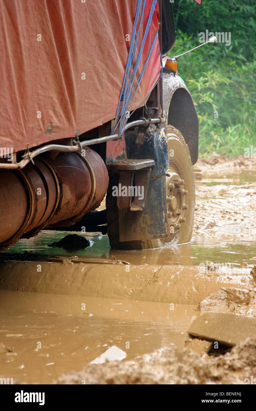 Truck on muddy dirt road driving through deep mud after rain during the ...