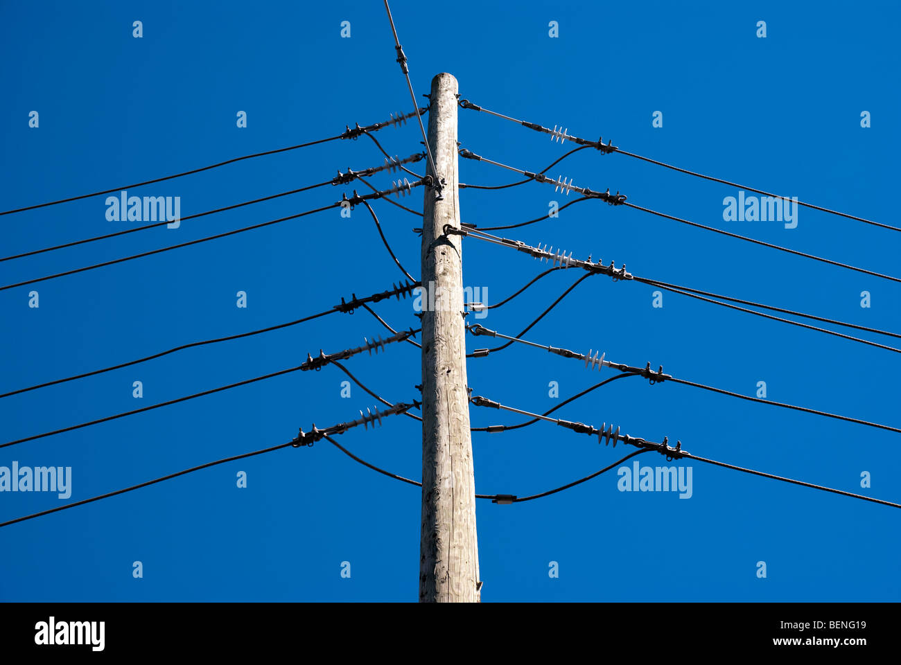 Wooden power lines pole against bright blue sky Stock Photo - Alamy