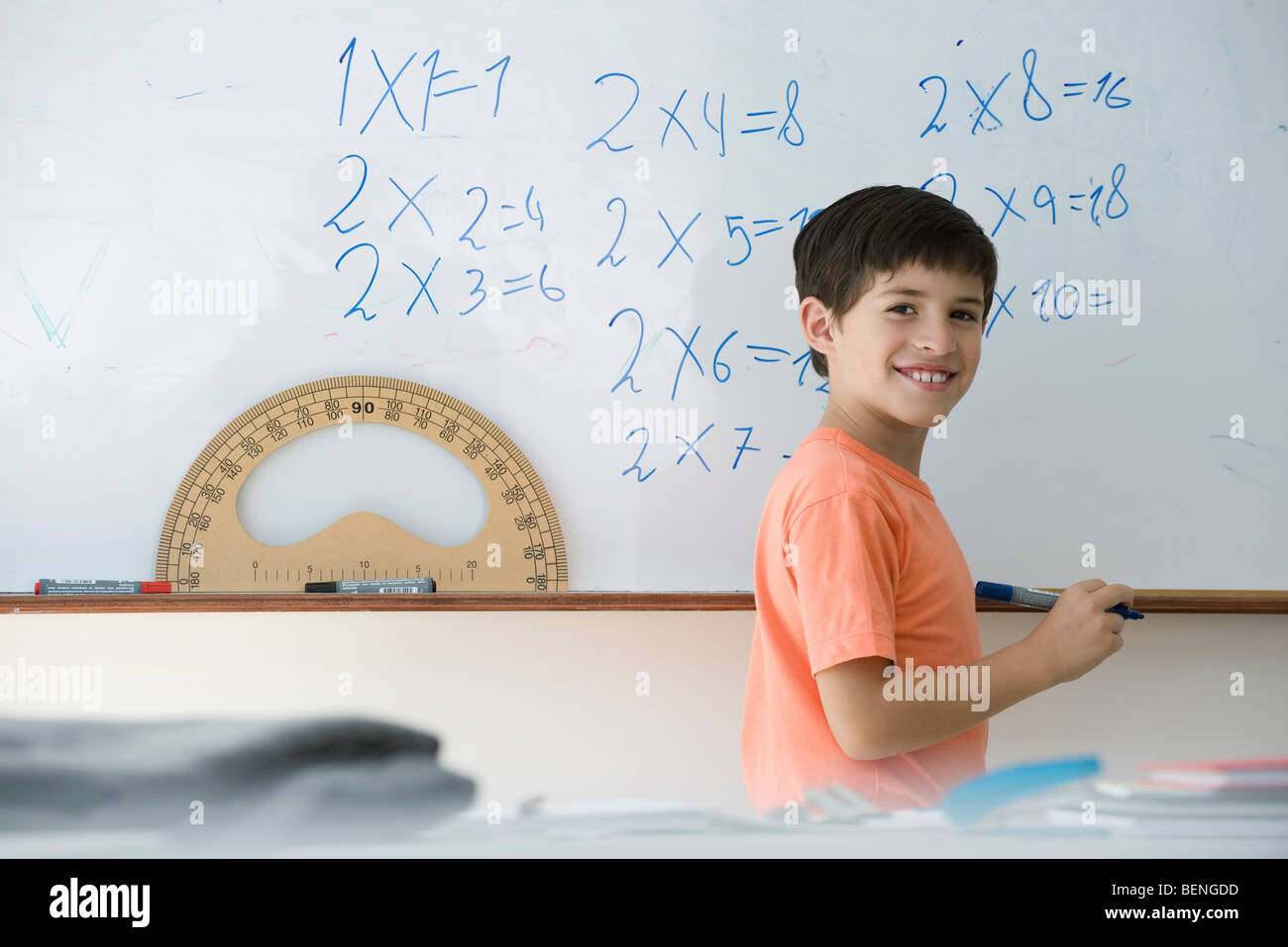 Elementary school student writing equations on whiteboard, smiling over ...