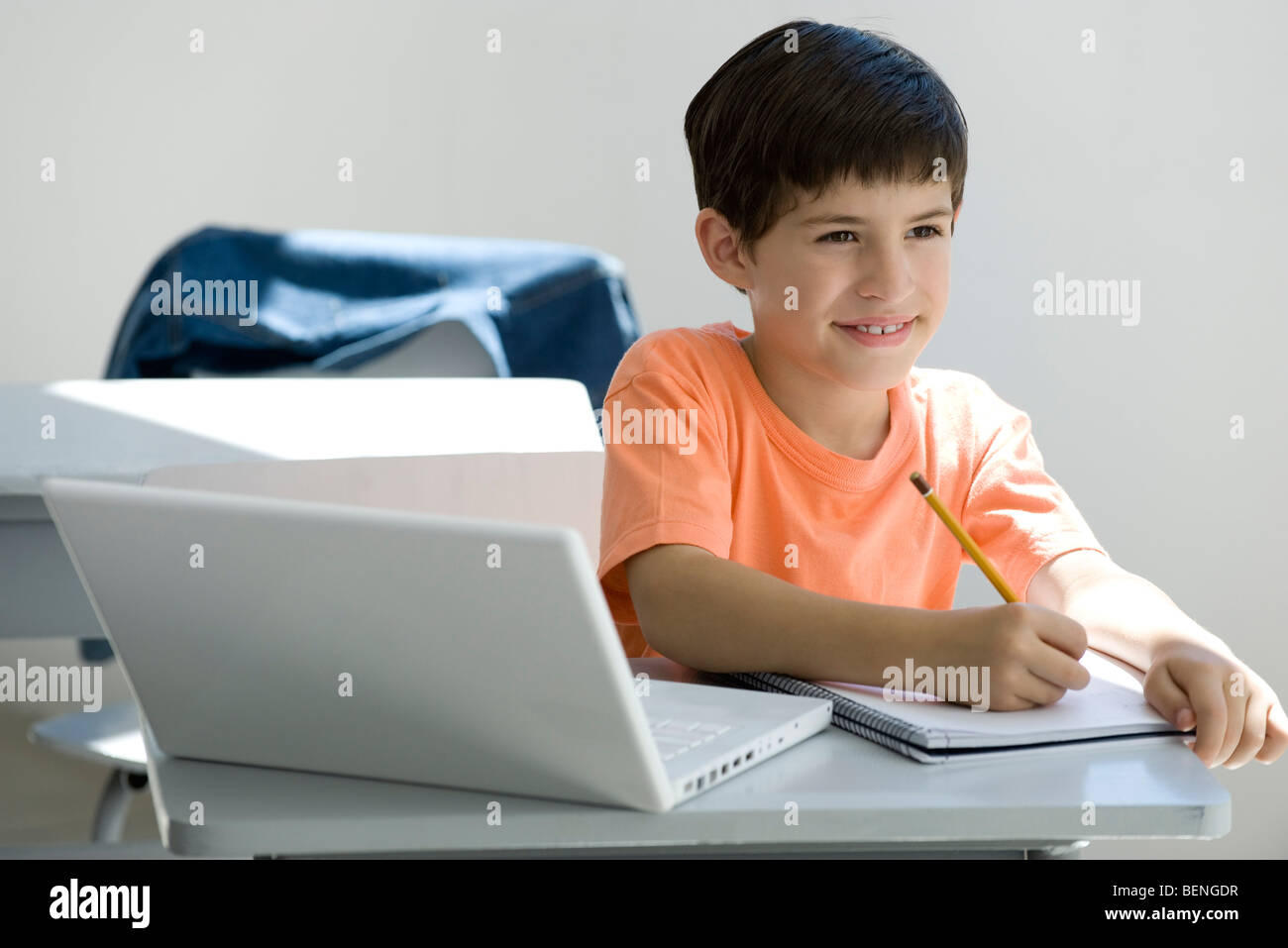 Elementary school student taking notes in class, laptop computer on ...