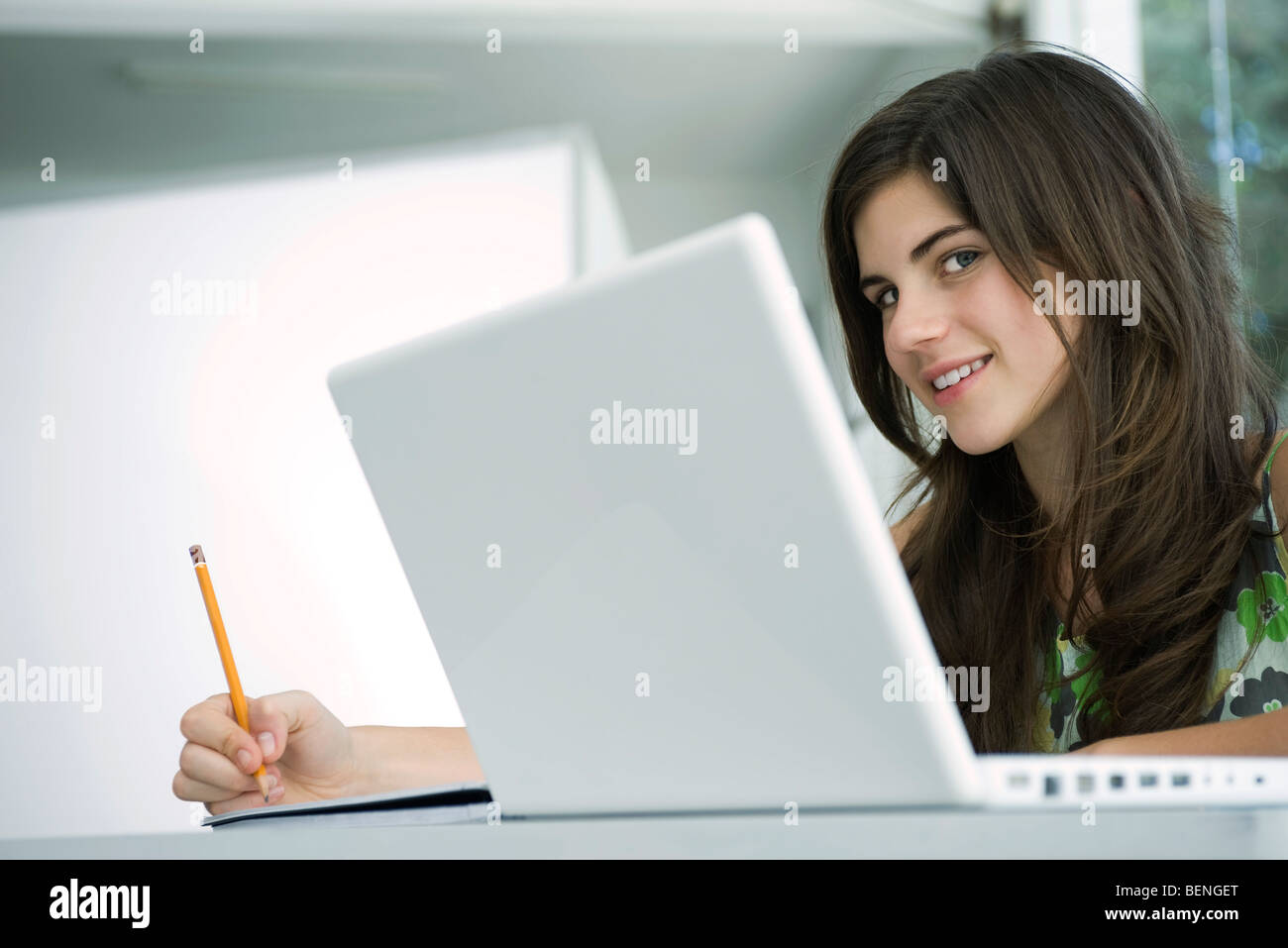 Teenage girl at desk writing, laptop computer in foreground Stock Photo ...